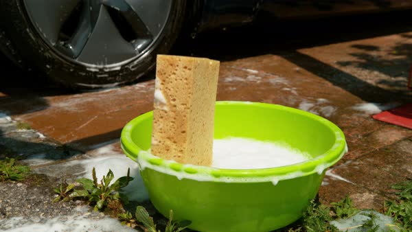 SLOW MOTION, CLOSE UP, DOF: Brown sponge falls into a bucket full of ...
