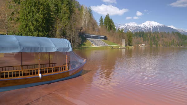 Scenic shot of snow capped mountains from the shore of red hued lake ...