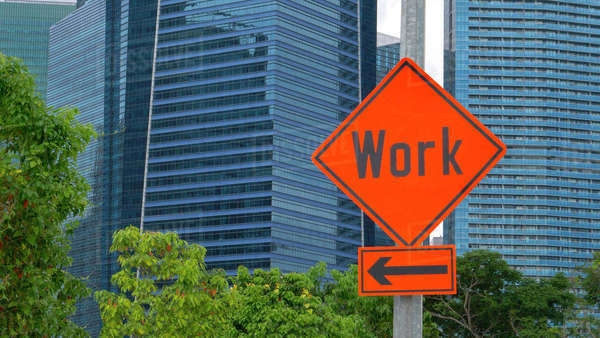 CLOSE UP: Bright orange traffic sign instructing traffic to go past ...