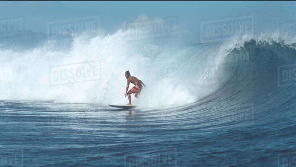 Active young man on surfboard rides a beautiful spraying tube wave all ...