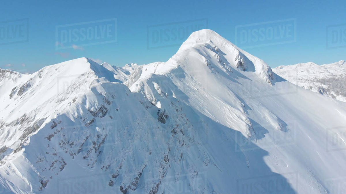 AERIAL: Cinematic shot of a majestic snowy mountain ridge in the ...