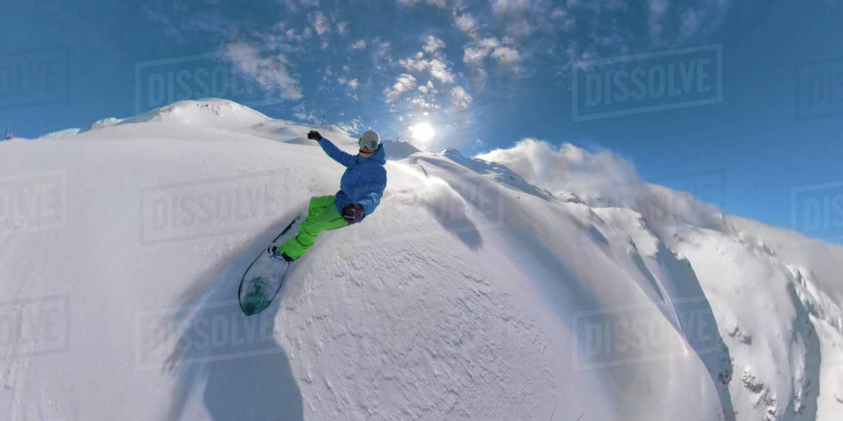 360 VIRTUAL REALITY: Young male snowboarder riding fresh powder snow in ...