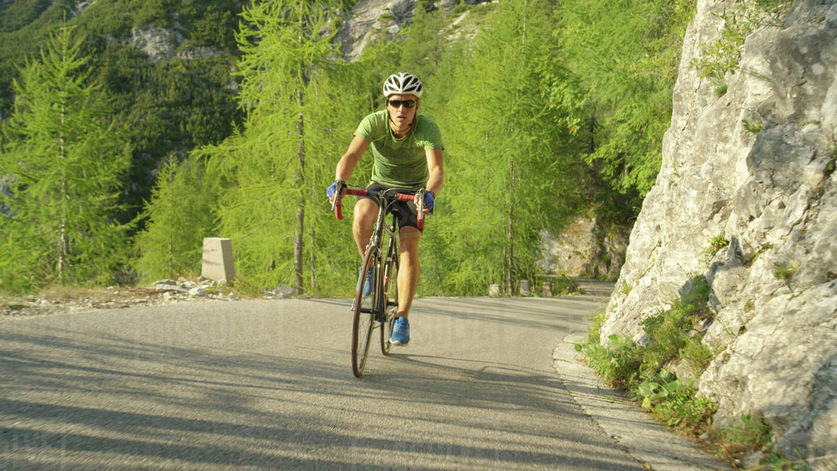 Professional road cyclist training for a long race through the sunny ...