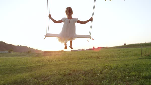 SLOW MOTION CLOSE UP Unrecognizable little girl swaying on a wooden ...