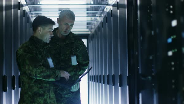 In data center two military men work with open server rack cabinet. One ...