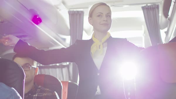 On a plane beautiful stewardess/flight attendant shows safety measures ...