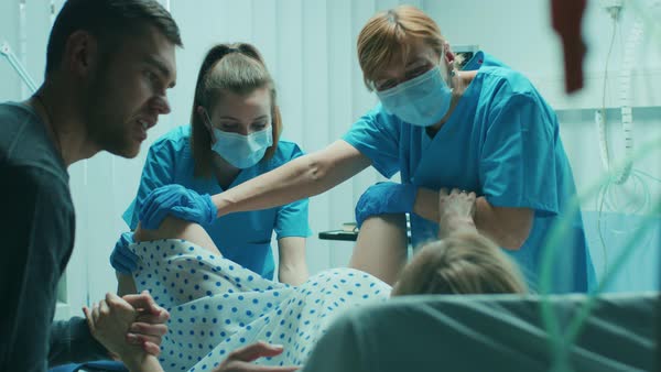 In the hospital woman in labor pushes to give birth, obstetricians ...