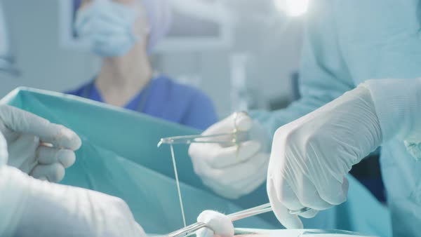 Close-up on professional surgeon suture wound after successful surgery ...