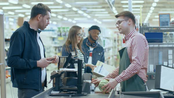 At the supermarket: checkout counter customer pays with smartphone for ...