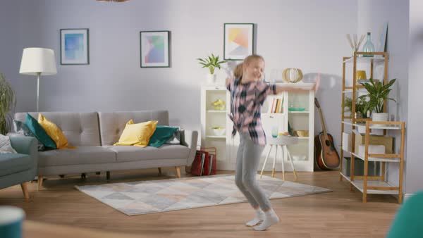 Cute happy girl dances in the middle of the living room. cheerful child ...
