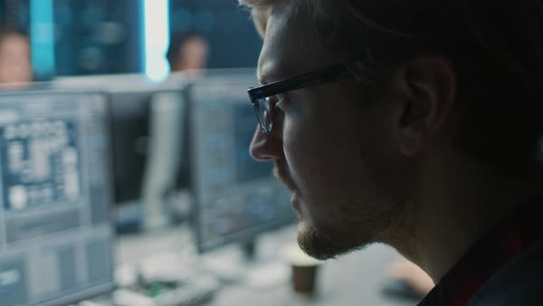 Smart male it programer working on desktop computer in data center ...