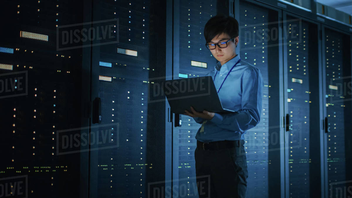 In Dark Data Center: Male IT Specialist Walks along the Row of ...