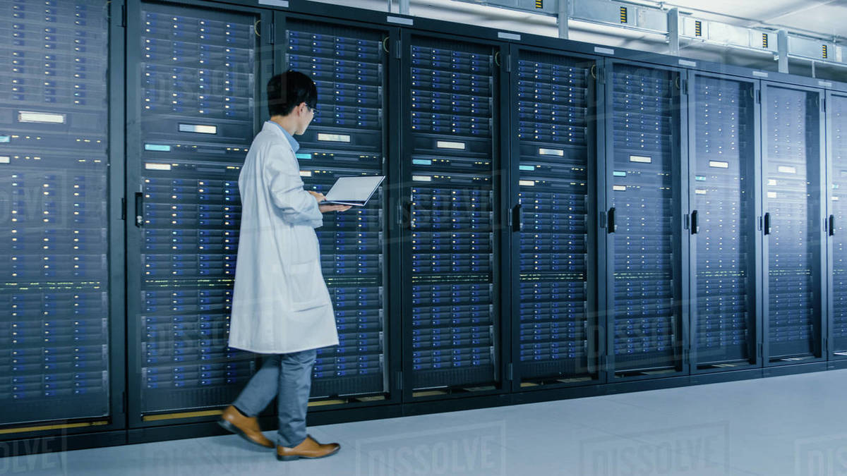 In Data Center: Male IT Specialist Wearing White Coat Walks Alongside ...