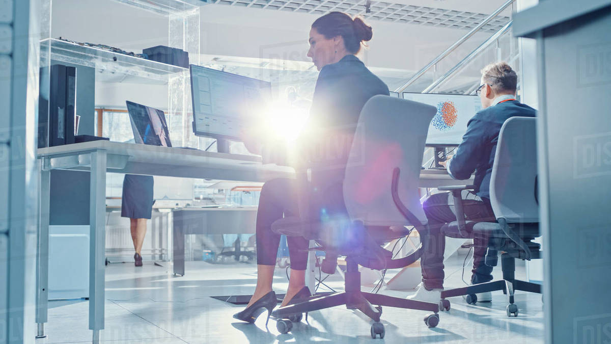 Back View of Team of Technology Engineers Working on Desktop Computers in Bright Office. Screens ...