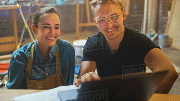 Couple of Artists Sitting in their Studio Use Laptop Computer, Working ...