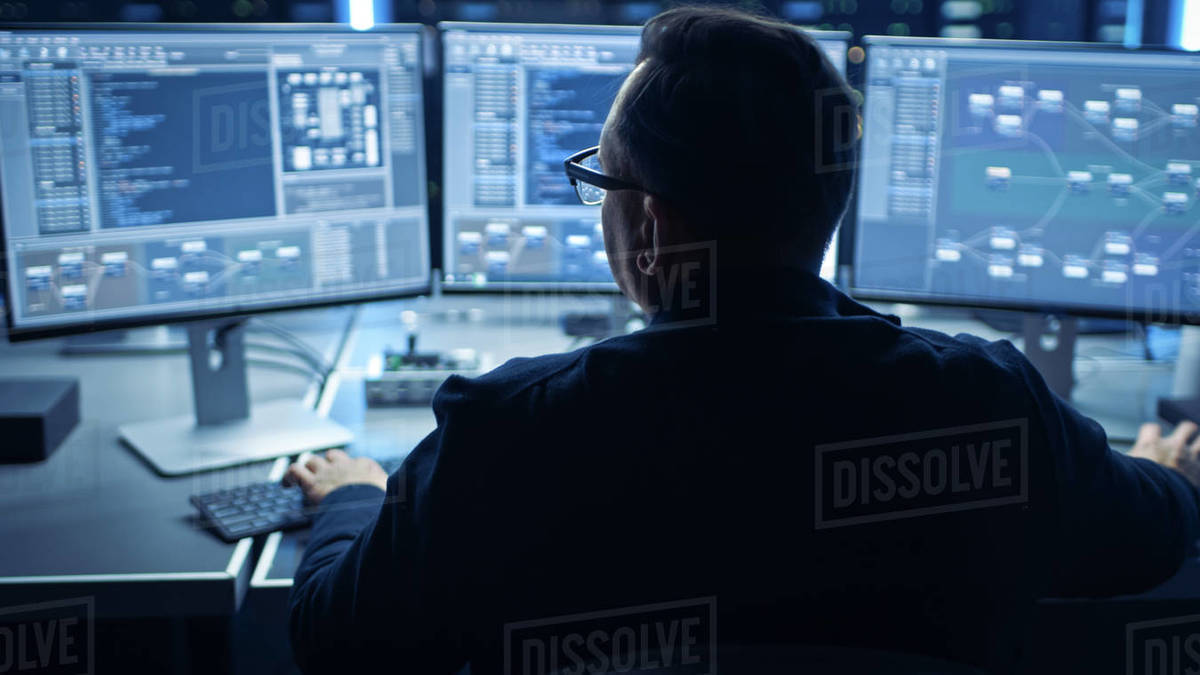 Professional IT Programer Working in Data Center on Desktop Computer with Three Displays, Doing ...