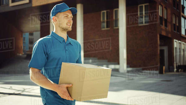Handsome Delivery Man Holds Cardboard Box Package Walks Through Modern ...