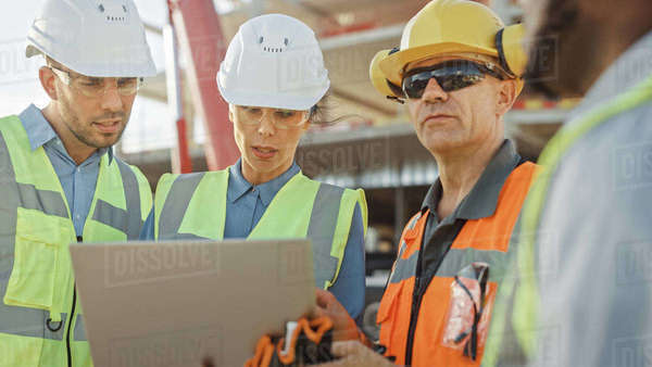 Diverse Team of Specialists Use Laptop Computer on Construction Site ...