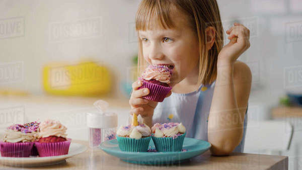 In the Kitchen: Adorable Little Girl Eats Creamy Cupcake with Frosting ...