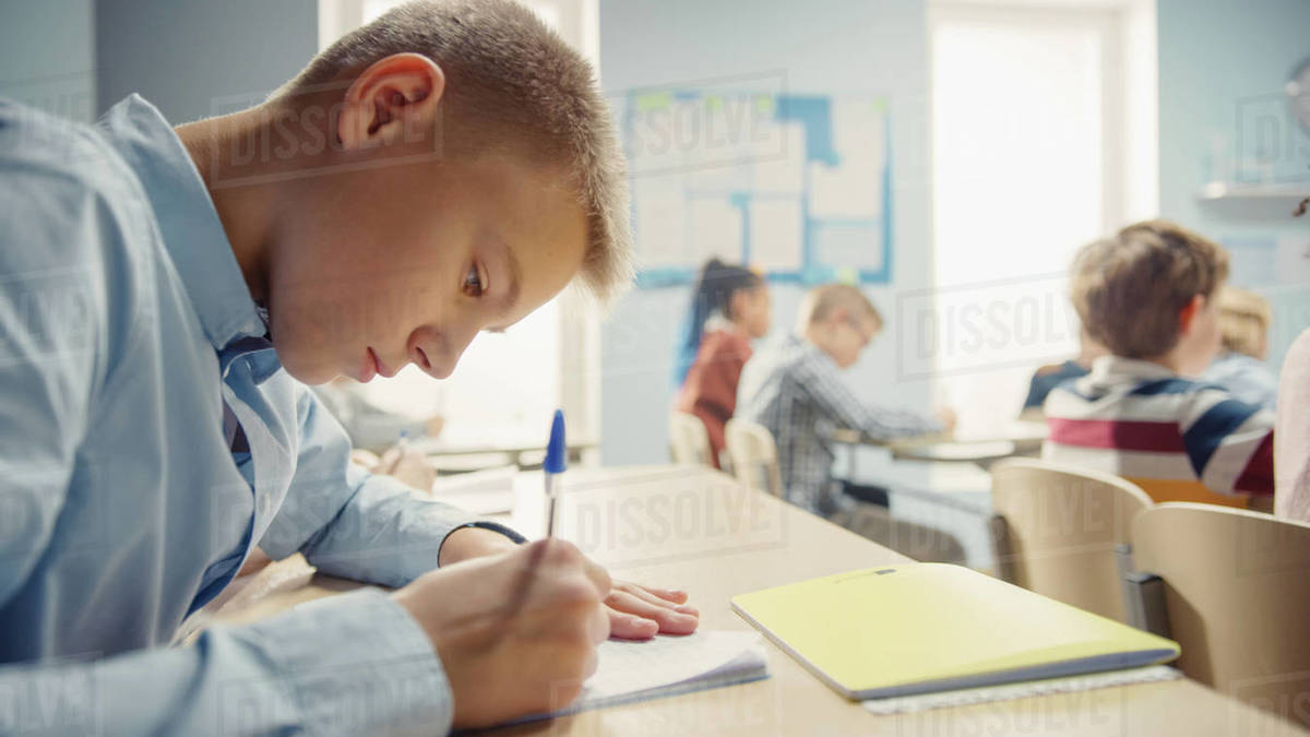 Shot of a Young Boy in School Writing in Exercise Notebooks, Taking a ...