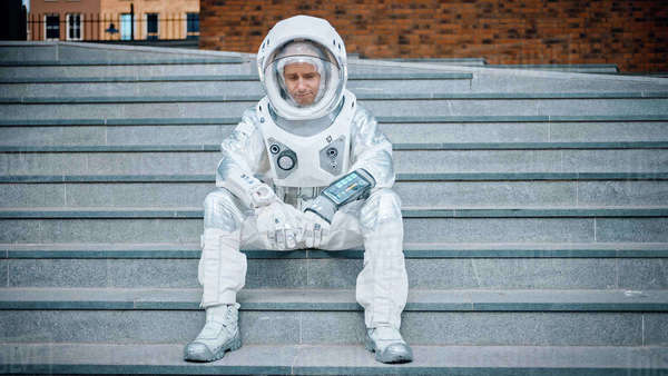 Sad Man in Spacesuit is Sitting on Concrete Stairs. Astronaut is ...