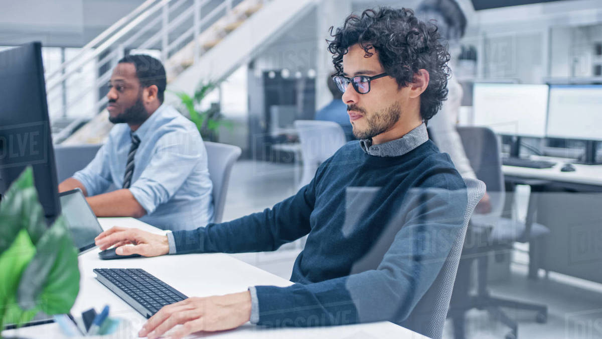 Young Handsome Manager with Curly Hair Works on a Desktop Computer and ...