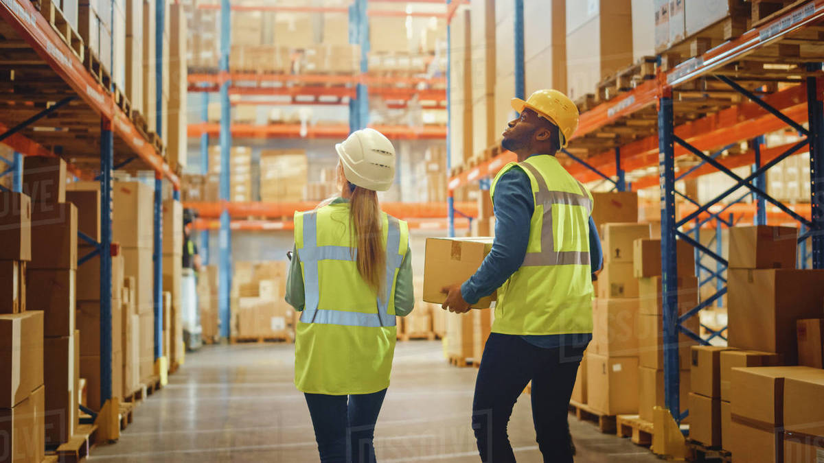 Male and Female Workers Wearing Hard Hats Walking Through Retail ...