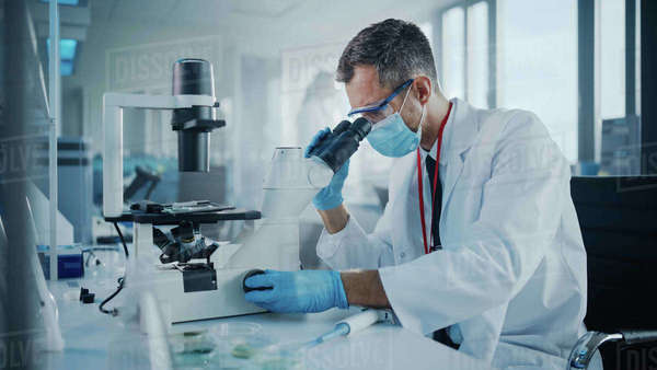 Scientist Wearing Face Mask Looking Under Microscope - Royalty-free ...