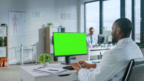 Medical Doctor is Working on a Computer with Green Screen Mock Up ...