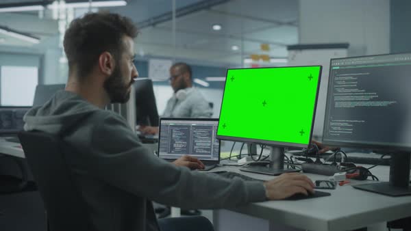 IT Programmer Working on Computer with Green Screen Chroma Key Display ...