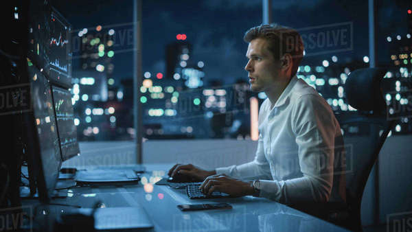 Financial Analyst Working on Computer with Multi-Monitor Workstation ...