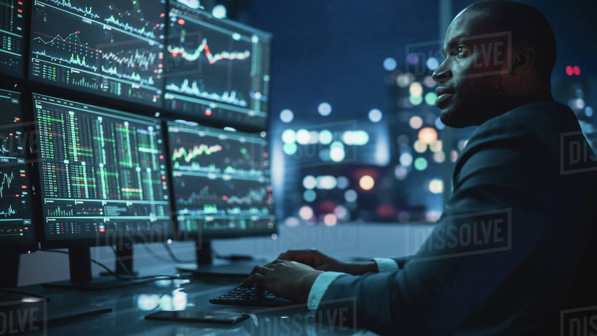 Financial Analyst Working on Computer with Multi-Monitor Workstation ...