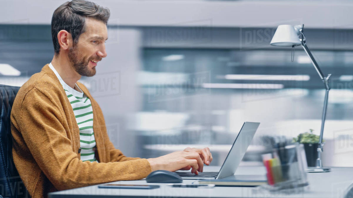 Businessman Sitting at His Desk Working on a Laptop Computer - Royalty ...