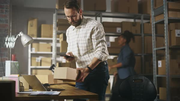 Storeroom Inventory Worker Using Smartphone to Scan a Barcode on Parcel ...