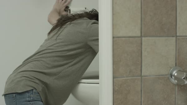 Medium shot of woman kneeling and vomiting in toilet - 4K Rights ...
