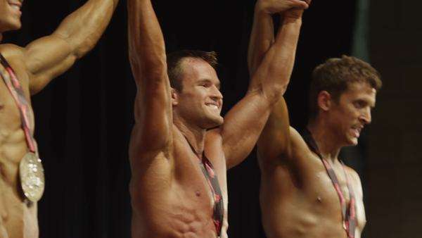 Low angle panning shot of winning bodybuilders posing on stage after ...
