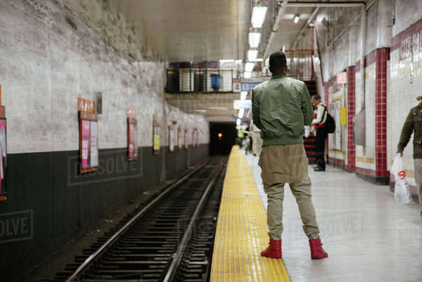 Rear view of a man standing at subway station - Stock Photo - Dissolve