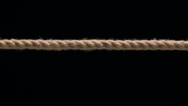 Close up of rope being pulled taut into frame against black - Stock ...