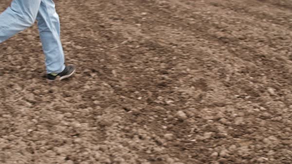 Farmer walking on farm land, planning new seeding season - HD Royalty ...