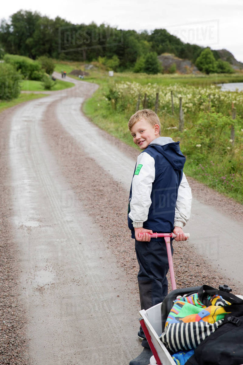 Boy pulling cart on dirt track - Royalty-free Stock Photo | Dissolve