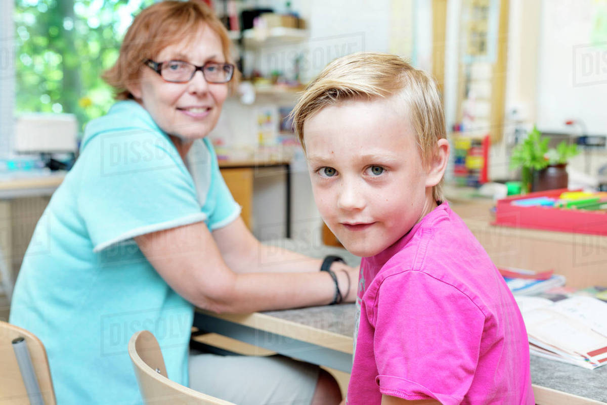 Boy and teacher sitting in classroom - Royalty-free Stock Photo | Dissolve