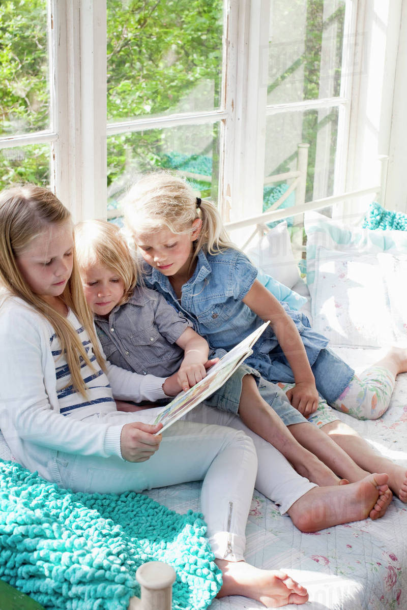 Three girls reading book - Stock Photo - Dissolve