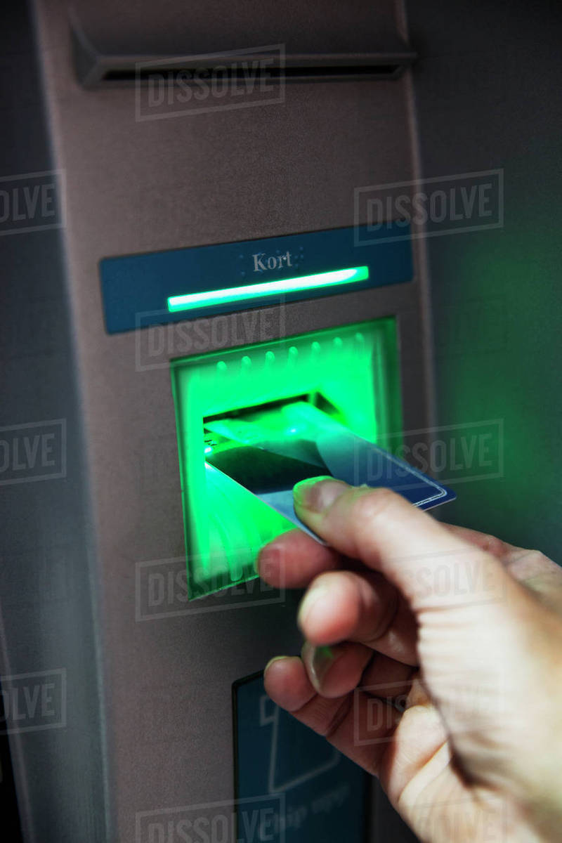 Hand putting bank card into cash machine - Stock Photo - Dissolve
