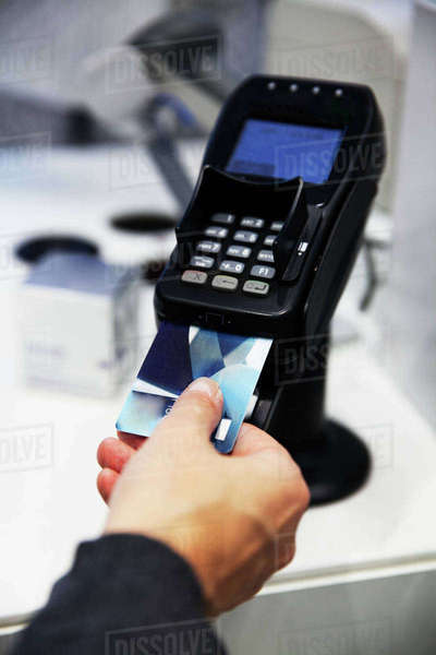Hand putting bank card into card reader - Stock Photo - Dissolve