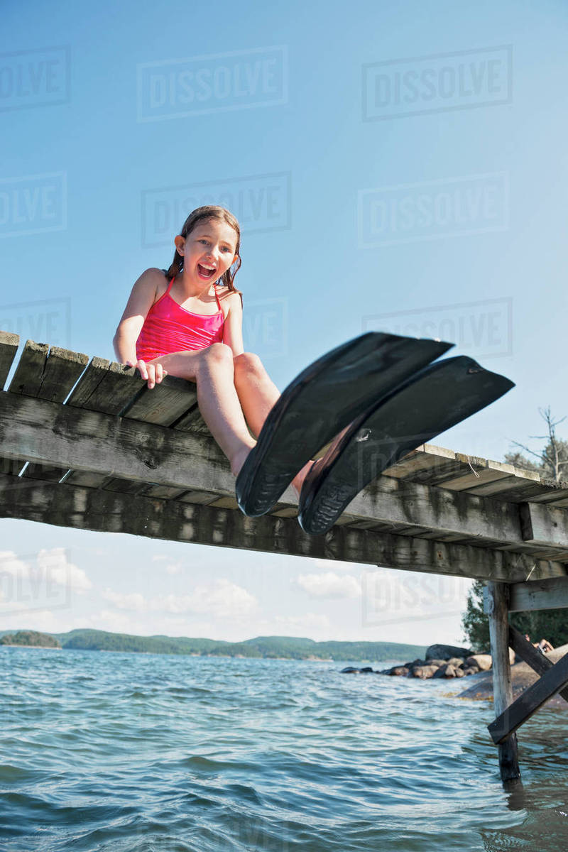 Happy girl wearing flippers on jetty - Royalty-free Stock Photo | Dissolve
