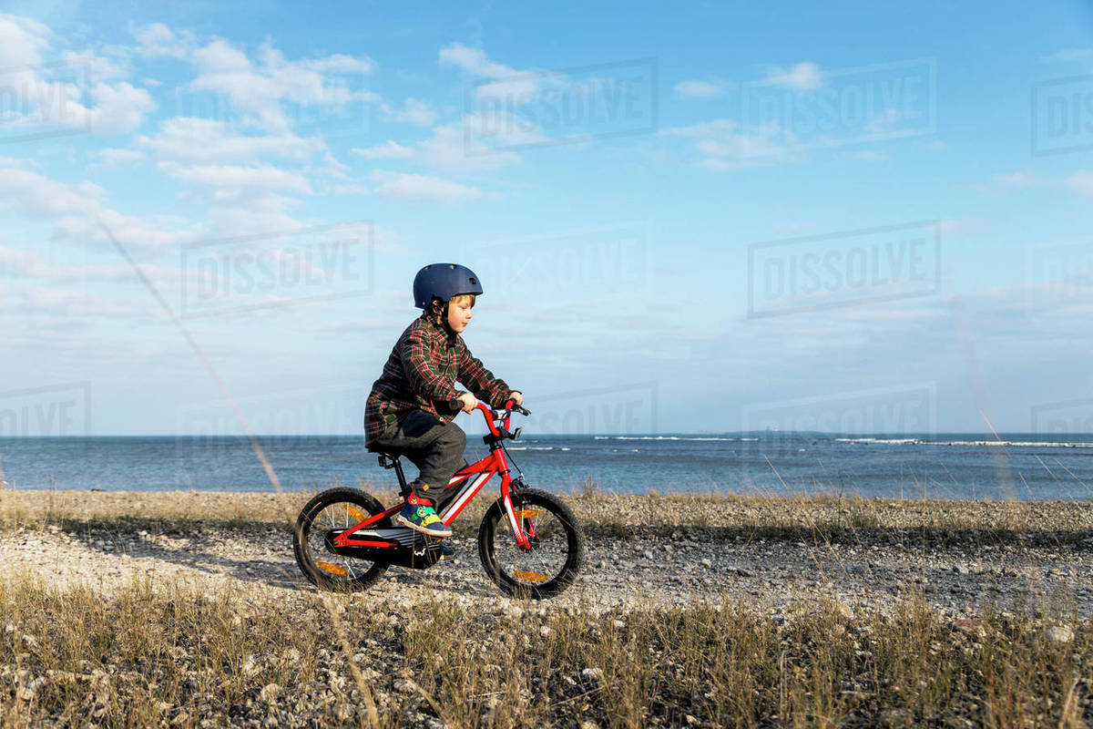 Boy cycling at sea - Royalty-free Stock Photo | Dissolve