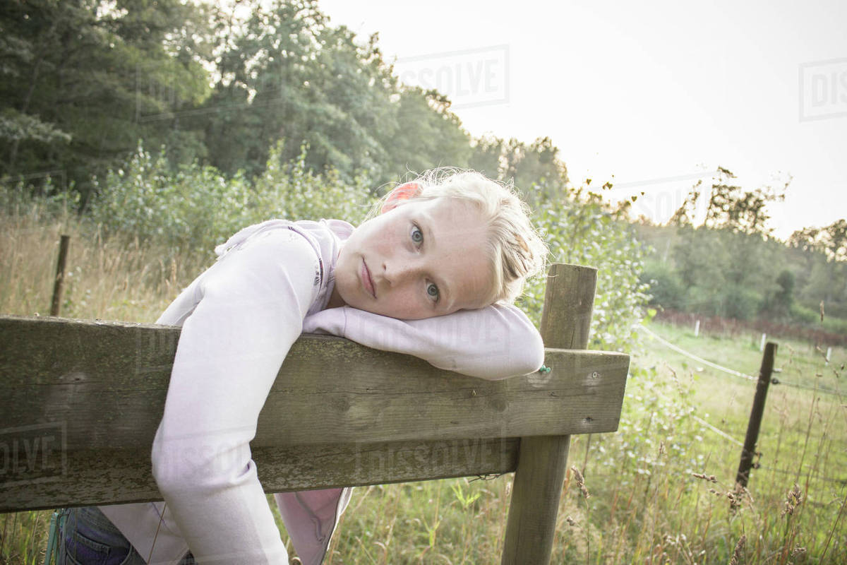 Girl sitting on bench and looking at camera - Stock Photo - Dissolve