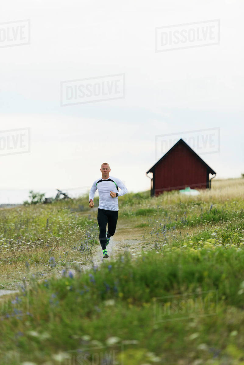 Young man running through meadow - Royalty-free Stock Photo | Dissolve