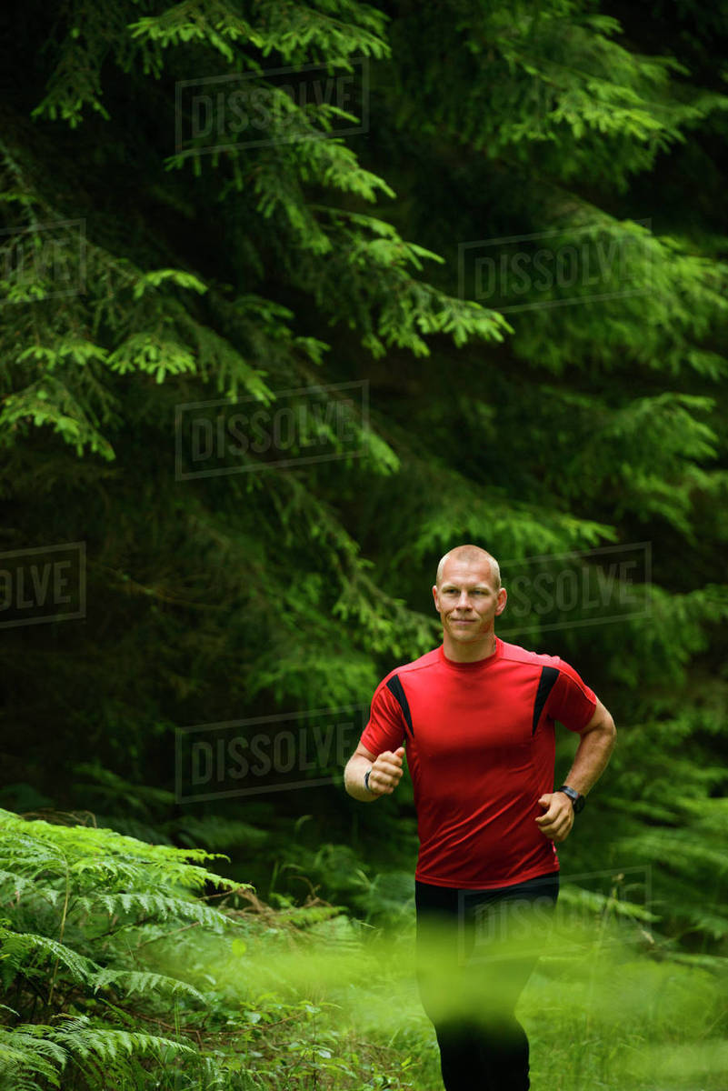 Young man running through forest - Stock Photo - Dissolve