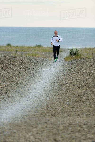 Man running through seaside footpath - Royalty-free Stock Photo | Dissolve